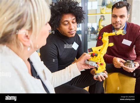 team of diverse professionals examining and discussing a robotic arm