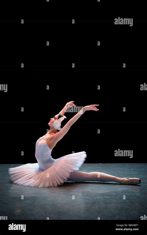 Ballet Dancer In White Tutu Performing Elegant Split On Dark Stage