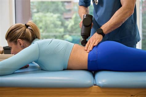 Male Therapist Massaging Female Spine And Lower Back With Massage Gun