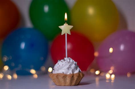 노란 별 모양의 촛불이 있는 축제 컵케이크 배경에 여러 가지 색상의 풍선과 조명 파티 생일 개념 공간을 복사합니다 고독 부정적인