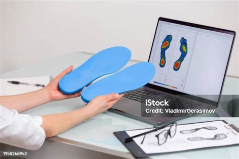 여성 정형외과 의사가 테스트 발 사진과 함께 노트북 앞에서 맞춤 제작 깔창을 들고 있습니다 발 레크리에이션 및 교정 의학 개념 안창에 대한 스톡 사진 및 기타 이미지
