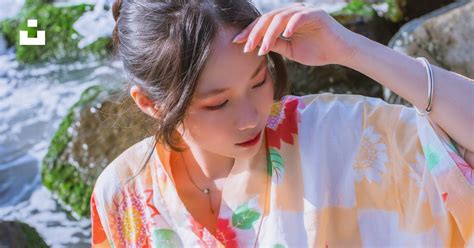 기모노를 입은 여자가 물가의 바위에 앉아 있다 사진 Unsplash의 무료 유행 이미지