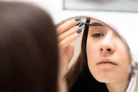 Premium Photo Young Woman Applies Makeup Looking In The Mirror Combs
