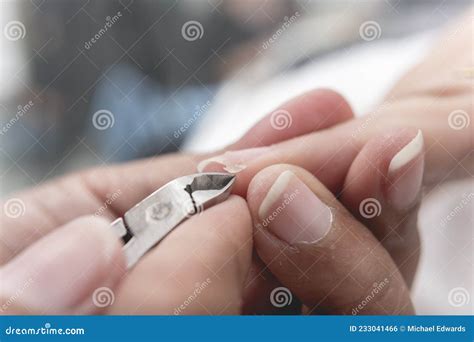 A Manicurist Uses A Pair Of Nippers To Remove A Hangnail From The Edge