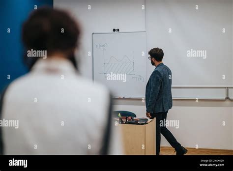 Teacher Explaining Graph On Whiteboard During Classroom Lesson Stock