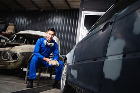 기업가 사업가 중소기업 소유자 차고 자동차 수리점 화가 점프 수트와 먼지 마스크를 착용 차고에 앉아 휴대 전화와 노트북을 사용합니다 30 34세에 대한 스톡 사진 및 기타