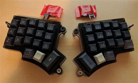 Two Computer Keyboards Sitting On Top Of A Wooden Table Next To Each Other With Red Clips