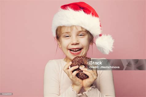 초콜릿 도넛을 들고 산타 모자에있는 귀여운 소녀 핑크 배경에 행복한 아이 12월에 대한 스톡 사진 및 기타 이미지 12월 4 5세 감정 Istock