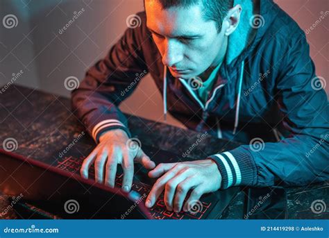 A Male Hacker Is Typing On A Laptop Keyboard In A Dark Room Under A Neon Light Cybercrime Fraud