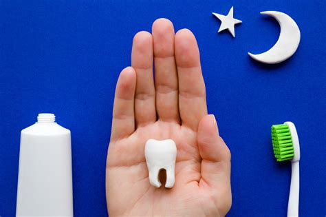 여자의 손 손바닥에 흰색 치아 녹색 칫솔모가있는 칫솔과 어두운 파란색 배경의 치약 튜브 달과 별 모양입니다 건강한 치아 저녁 위생 개념 하향하 보기 근접 촬영 치과 장비에