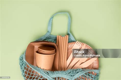 친환경 식기의 최고 전망 복사 공간이있는 밝은 녹색 배경에 파란색 면 그물 가방에 나무 칼붙이와 크래프트 종이 식품 컵과 용기