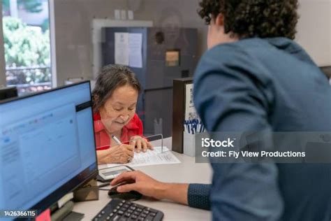 의료 클리닉 접수 데스크에서 서류 작업에 서명하는 노인 여성 안내 데스크에 대한 스톡 사진 및 기타 이미지 안내 데스크