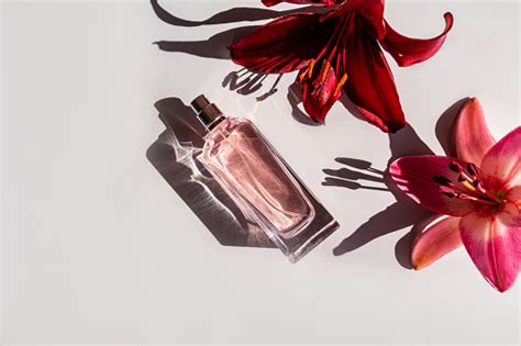 백합의 꽃 냄새가 나는 여성 향수 또는 화장실 물의 투명한 병 베이지 색 배경 공간의 복사본입니다 향수를위한 템플릿 향수병에