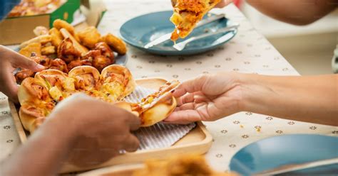 행복한 아프리카 가족 부모와 두 어린 딸이 함께 프라이드 치킨과 피자를 먹고 있습니다 아버지와 어머니와 귀여운 아이 소녀 아이가 집에서 함께 먹고 즐겁게 식사를 나누고