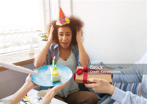 파란 셔츠에 있는 소녀는 오늘 생일이 있습니다 그녀의 친구는 그녀를 위해 약간의 놀라움을 만들었습니다 그들은 현재와 촛불을 가진 케이크 한 조각을 들고 있습니다 생일 길r은