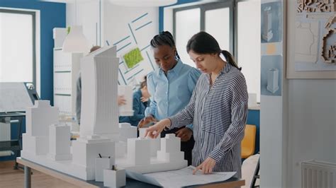 Premium Photo Multi Ethnic Women Analyzing Building Model And Blueprints Plan To Develop