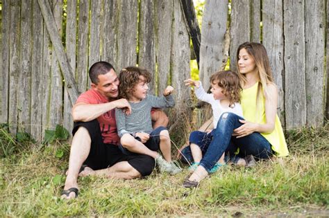 Familia Joven Hermosa Contra La Cerca De Madera Vieja Naturaleza Del Verano Foto De Archivo