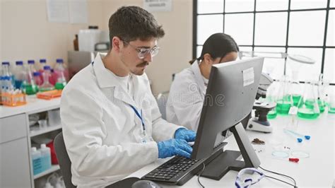A Man And Woman Scientists In Lab Coats Analyzing Data On A Computer In A Modern Laboratory