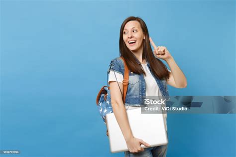 젊은 배낭 들고 파란색 배경에 고립 된 노트북 Pc 컴퓨터를 새로운 아이디어 포인팅 검지 손가락을 데 귀여운 여자 학생을 흥분 대학에서 교육입니다 광고에 대 한 공간을 복사