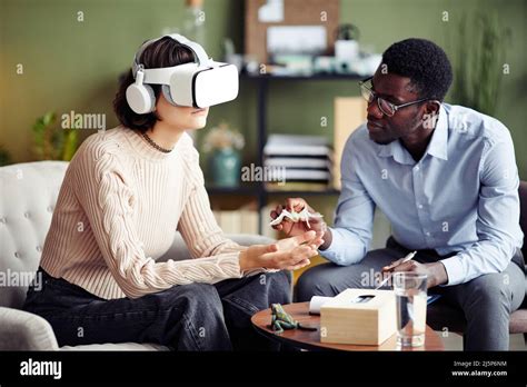 Software Developer Giving Plastic Spider To Young Woman Wearing Virtual Reality Headset Stock
