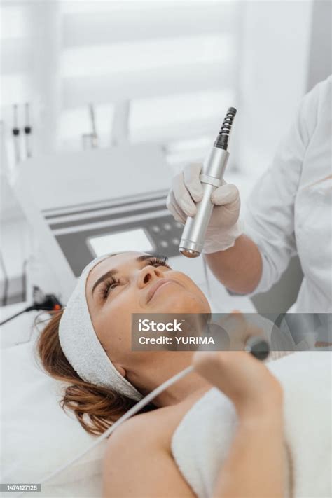주사 메조 테라피가없는 전기 천공 여성 미용사는 주름을 줄이고 소녀 얼굴을 복원 재생 및 젊어지게하기 위해 얼굴 피부에 미용 절차를 수행합니다 미용 클리닉 2명에 대한 스톡