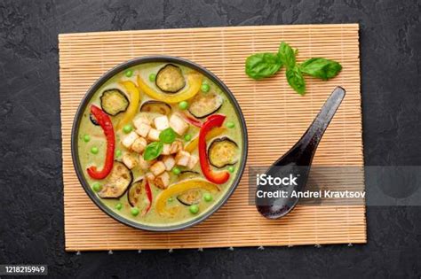 어두운 슬레이트 배경에 검은 그릇에 두부와 채식 타이어 녹색 카레 채식 그린 타이 카레는 녹색 칠리 페이스트 바질 향신료와 야채와 태국 요리 요리입니다 태국 음식 그린