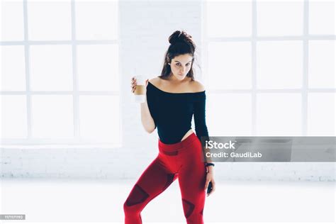 트렌디 한 활동적인 착용에 동기를 부여 스포츠 여성의 절반 길이 초상화 는 훈련에 물을 마시는 휴식을 갖는 심각한 여성은 음료와 컵을 들고 카메라를보고 하드 운동에 만족