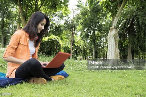 녹색 잔디에 젊은 여 자가 앉아 노트북 야외 자유와 휴식 개념으로 음악을 즐길 수 꽃 식물에 대한 스톡 사진 및 기타 이미지 꽃 식물 데이지속 듣기 Istock