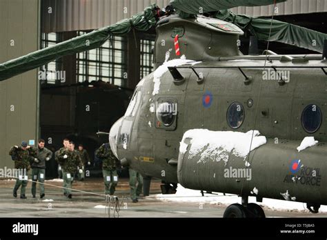 Raf Personnel Walking Out Of A Hanger In The Snow Past A Chinook Helicopter At Raf In Hampshire