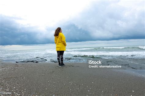 비오는 날 바닷가에 홀로 서 있는 노란 비옷을 입은 긴장된 젊은 여자 가을에 대한 스톡 사진 및 기타 이미지 가을 겨울 코트 경관 Istock