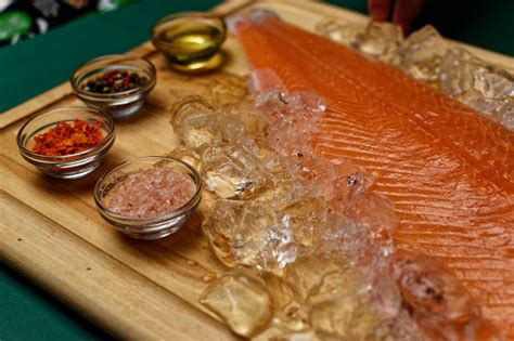 연어 필레 핑크 소금 기름 다채로운 후추 말린 당근을 얼음이 있는 나무 판에 유리 그릇에 담습니다 건강관리와 의술에 대한 스톡