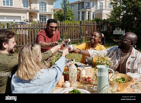 Young Interracial Friends With Glasses Of Homemade Wine And Bottles Of