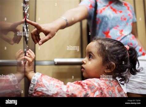 Woman Pressing Push Button While Babe Looking In Elevator Stock Photo Alamy