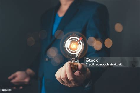 전문가는 비즈니스 목표와 전략 계획을 나타내는 목표 기호가 있는 빛나는 전구를 들고 경쟁이 치열한 환경에서 성공하기 위한 혁신 초점 및 결단력을 보여줍니다 가상현실에 대한