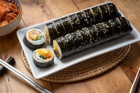 한국 스시 롤 또는 김밥은 나무 테이블에 흰색 접시에 인기있는 한국 요리 캘리포니아 마키 새우 계란 고기와 야채로 해초로 싸인 찐 쌀입니다 건강한 식생활에 대한 스톡 사진