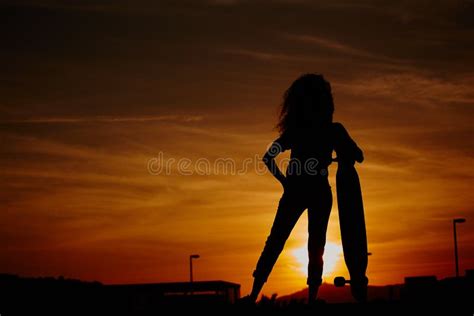 Силуэт молодой девушки битника с Longboard в заходе солнца Стоковое Фото изображение
