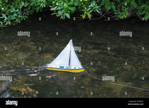 A Small Attractive Model Sailing Boat On A String Floating In A Stream