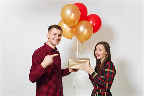 아름 다운 젊은 행복 미소 커플 사랑에 여자와 남자와 황금 선물 상자를 들고 제시 하 고 빨강 노랑 흰색 바탕에 생일 축 하