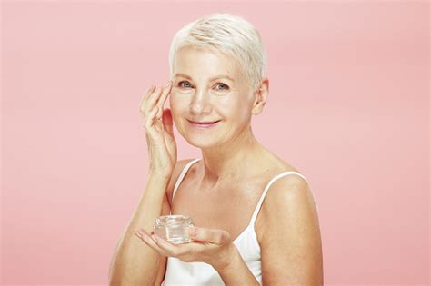 분홍색 배경에 고립된 얼굴에 보습 크림을 바르는 고위 여성 50 59세에 대한 스톡 사진 및 기타 이미지 50 59세 60 64세 60 69세 Istock