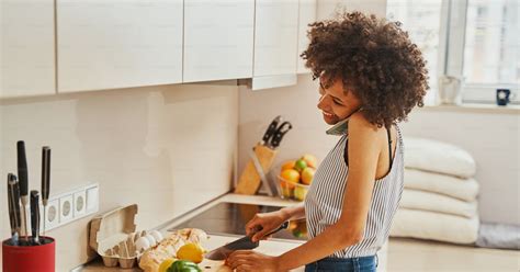 스마트폰을 귀에 대고 손에 칼을 들고 부엌 조리대에 서 있는 웃는 여자 사진 Unsplash의 아프리카 계 미국인 여성 이미지