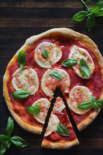 얇게 썬 갓 구운 수제 마르게리타 피자 골든 버팔로 모짜렐라 치즈 서클 풍부한 토마토 마리나라 소스 신선한 바질 잎 토핑 나무 도마 배경 높은 전망 마르게리타 피자에 대한