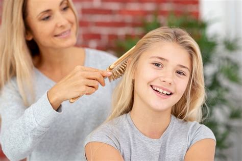 Madre Rubia Peinando El Cabello De Su Hija Foto Gratis