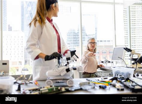 Female Engineers Talking And Assembling Robotics In Highrise Office