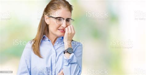 아름 다운 중간 나이 성숙한 비즈니스 여 자가 입을 물고 손톱에 손으로 스트레스와 긴장을 찾고 고립 된 배경 위에 안경을 착용