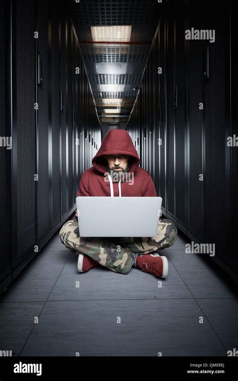 The Hacker In A Hood Sits With The Computer Among Servers The Burglar
