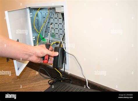 The Router Box Is Open The Human Hand Holds A Screwdriver There Is A Black Router Next To It