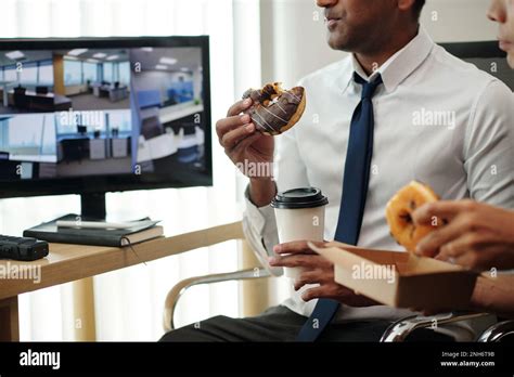 Cropped Image Of Security Guards Eating Sweet Donuts When Watching