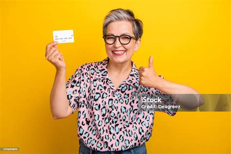 매력적인 연금 수령자 여자 신용 카드 엄지 손가락 위로 착용 유행 표범 인쇄 옷 노란색 배경에 고립 된 사진 초상화 50 54세에 대한 스톡 사진 및 기타 이미지 Istock