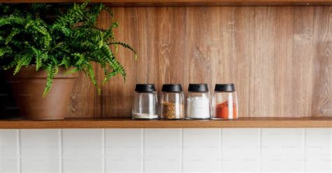 현대적인 주방 조리대에 후추 밀과 칼이 있는 나무 판과 유리 병에 음식 재료와 향신료가 있는 선반 스칸디나비아 스타일의 세련된
