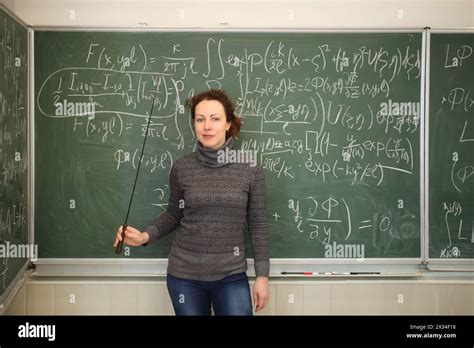 Teacher With Pointer Stands Near Blackboard With Mathematics Formulas